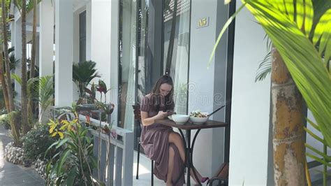 Tropical Country Bungalow Girl With A Phone Sitting On The Veranda