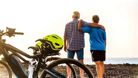 두 선배는 우정과 사랑에 푹 빠졌습니다 조부모 전자 자전거와 하드 여행 후 휴식 물 위에 수평선을 찾고 노인과 여자의 커플 여자 노인에 대한 스톡 사진 및 기타 이미지