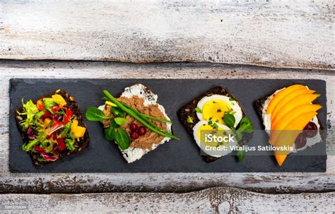 진한 호밀 빵으로 건강한 샌드위치를 엽니다 검은 접시에 다채로운 샌드위치의 다른 종류 망고 사과 체리 계란 샐러드 아보카도 및 기타 과일과 야채와 샌드위치 0명에 대한 스톡