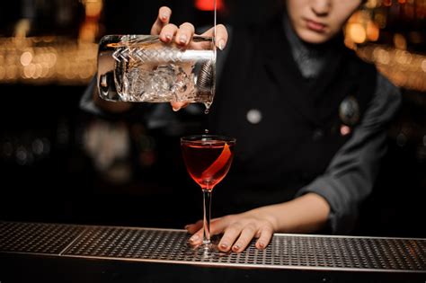 측정 유리 컵에서 스 트레이너를 거쳐 칵테일까지 알코올을 붓는 전문 여성 바텐더 각얼음에 대한 스톡 사진 및 기타 이미지