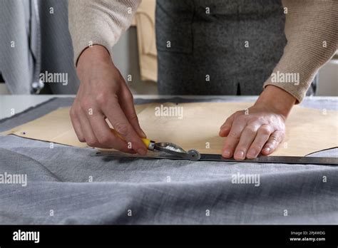 Tailor Transferring Sewing Pattern Onto Fabric With Tracing Wheel In
