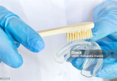 리테이너를 삽입하는 치과 의사 파란색 장갑을 낀 의사의 손에 나무 칫솔이 있는 마우스 가드 십대 교정 클리어 얼라이너 치과 야간 경비대 구강 건강 관리 개념 개선에 대한