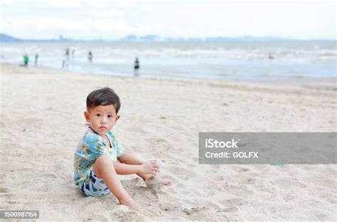 카메라를 들고 해변에서 모래를 가지고 즐거운 시간을 보내는 작은 아시아 아기의 초상화 아시아에 대한 스톡 사진 및 기타 이미지 아시아 아이 완구류 Istock