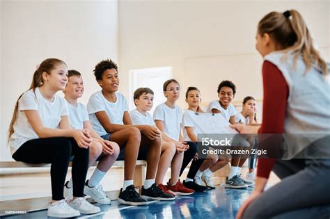 학교 체육관에서 체육 수업 중에 스포츠 선생님의 말을 듣고 있는 행복한 아이들 건강한 생활방식에 대한 스톡 사진 및 기타 이미지 건강한 생활방식 교사 교육 관련 직업