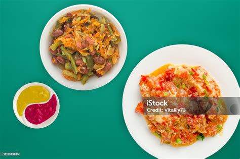 색깔의 배경에 흰색 접시에 양파와 토마토를 조인 양파 탑 뷰가 있는 토마토를 조림합니다 채식 음식 건강한 식생활에 대한 스톡