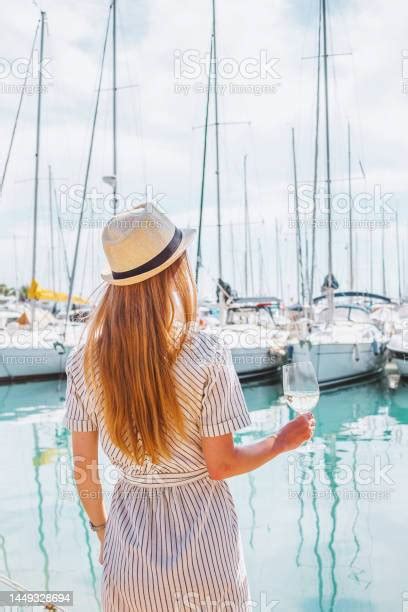 모자를 쓴 금발 머리 여자는 바다 요트 건물 및 보트 배경에 등을 대고 서 있습니다 유럽에서의 휴가 니스 프랑스 리비에라 여행 사진 관광 리조트에 대한 스톡 사진 및 기타
