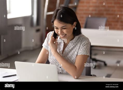 Happy Female Employee Speak On Cellphone Working On Laptop Stock Photo Alamy