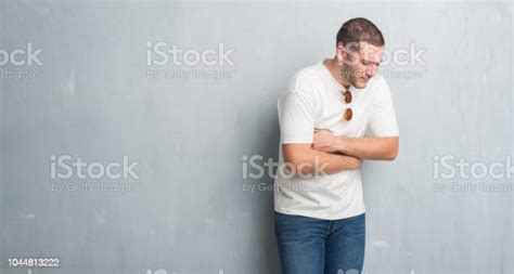 젊은 백인 남자 때문에 속에 손으로 선글라스를 입고 회색 그런 지 벽에 구역 질 고통 스러운 질병 기분이 나쁘다 통증 개념입니다 건강관리와 의술에 대한 스톡 사진 및 기타