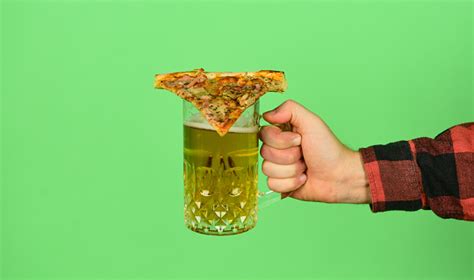 가져 가세요 남성 손은 맥주 한 잔과 피자 조각을 손에 들고 있습니다 펍에서 완벽한 휴식 피자를 먹고 맥주를 마십니다 마지막으로 피자 시간 피자는 공유 할 때 더 낫다 피자