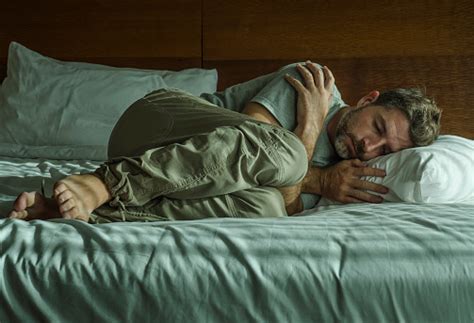 젊은 매력적인 슬프고 우울한 남자의 극적인 라이프 스타일 초상화 는 그늘진 빛에 압도과 절망적 인 고통 우울증 문제를 느끼고 집 침실에서 침대에 무력 울고 가리기에 대한