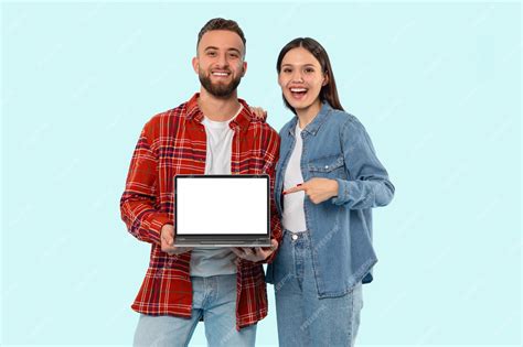 Premium Photo Couple Displaying Laptop Screen To Viewer On Blue