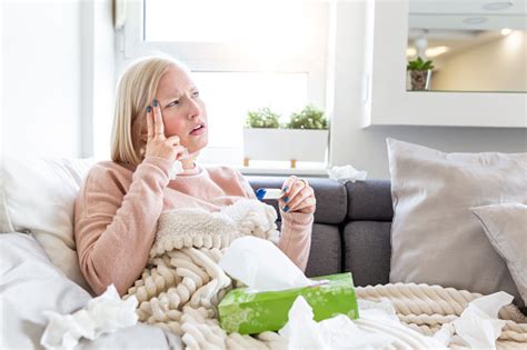 질병 계절 바이러스 문제 개념 온도계의 온도를 보고 소파에 누워 독감에 걸린 여자 고열로 침대에 누워 아픈 여자 감기 독감과 편두통 가정의 방에 대한 스톡 사진 및 기타