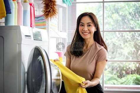 笑得开心的亚洲美女在洗衣房用洗衣机洗衣服高清图片下载 正版图片 摄图网