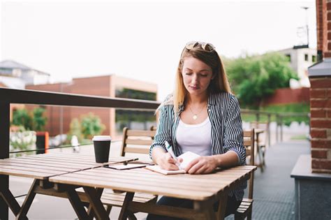 좋아하는 카페테리아에서 시간을 즐기는 사려 깊은 여성 캐주얼 수첩에 쓰기 조직 계획 테이블에 앉아 교과서 야외에서 공부하는 집중 여학생 계획에 대한 스톡 사진 및 기타