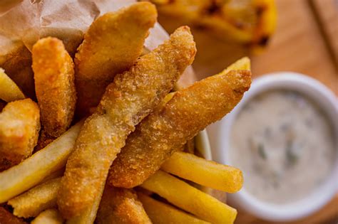 접시에 감자 튀김과 함께 반죽에 튀긴 대구 흰색 세라믹 냄비에 마늘 소스와 함께 나무 보드에 양피지와 함께 나무 배경입니다 0명에 대한 스톡 사진 및 기타 이미지 Istock