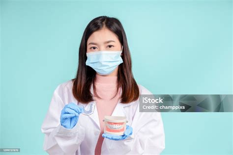 아시아 치과 의사는 파란색 배경 고립 된 스튜디오 샷에 올바른 치열 교정 치료 후를 포함하여 구강 및 치과 치료를 돌보는 방법을 가르치고 있습니다 건강 진단에 대한 스톡