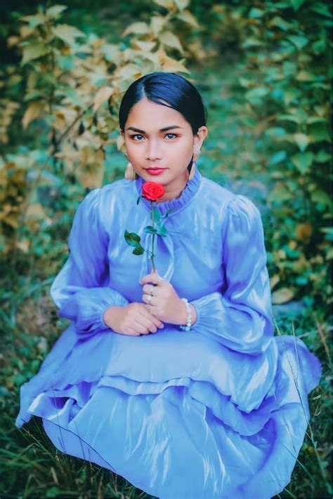 푸른 잔디 위에 앉아 있는 파란 드레스를 입은 소녀 · 무료 스톡 사진