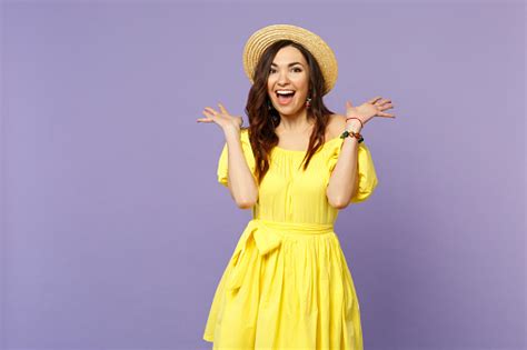 노란 드레스에 쾌활 한 재미 젊은 여자의 초상화 여름 모자는 손을 확산 파스텔 보라색 배경에 고립 된 카메라를 찾고 사람들은 진심으로 감정 라이프 스타일 개념입니다 복사