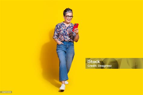전체 크기 사진 좋은 연금 수령자 여성 산책 보류 가제트 착용 유행 다채로운 복장 노란색 배경에 고립 된 50 54세에 대한 스톡 사진 및 기타 이미지 Istock