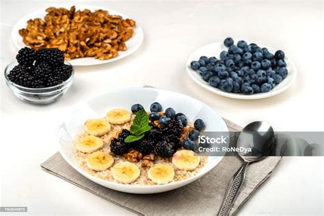 바나나 호두 블랙베리 블루베리 꿀 민트가 있는 오트밀 죽이 흰색 바탕에 흰색 그릇에 담았습니다 건강한 아침 식사와 수제 다이어트 음식 0명에 대한 스톡 사진 및 기타 이미지
