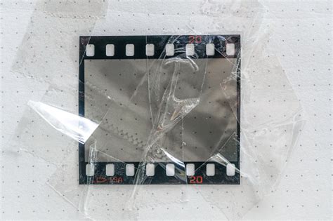 흰색 종이 배경에 실제 및 원래 35mm 또는 135 필름 재료 또는 사진 프레임 가장자리에 셀로 테이프가있는 빈 창 또는 셀이있는 35mm 필름 스트립 0명에 대한 스톡
