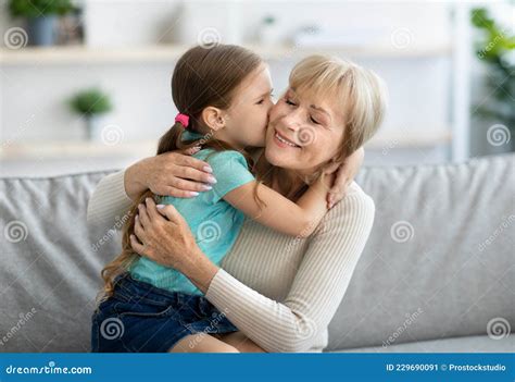 Happy Granddaughter Kissing Granny In Cheek At Home Stock Image Image