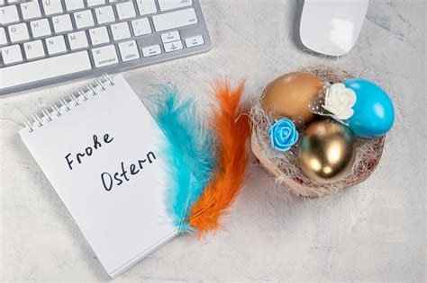 사무실에서 부활절 둥지와 색깔의 깃털에 색깔의 계란이있는 바탕 화면에 노트북에 독일어 프로헤 오스테른 또는 해피 부활절단어