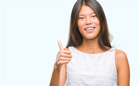 행복 한 엄지손가락 손으로 제스처를 하 고 격리 된 배경 위에 젊은 아시아 여자 승인 성공을 보여주는 카메라를 보고 하는 식 긍정적인 감정 표현에 대한 스톡 사진 및 기타
