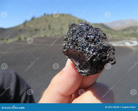 Fingers Holding A Piece Of Shiny Basaltic Lava Rock Outdoors Stock