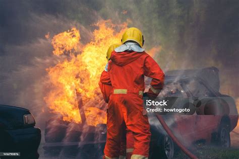 소방관 소방 소화기에서 구조 훈련 소방 호스 화학 물 거품 스프레이 엔진을 사용하여 화염으로 싸우는 소방관 소방관은 보호를 위해 단단한 모자 안전 복 유니폼을 착용합니다 2