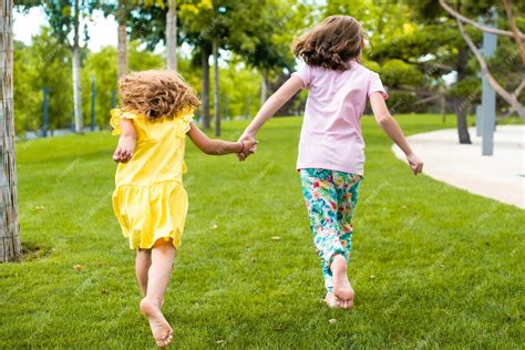 Premium Photo Sisters Are Walking Barefoot In The Grass In Park