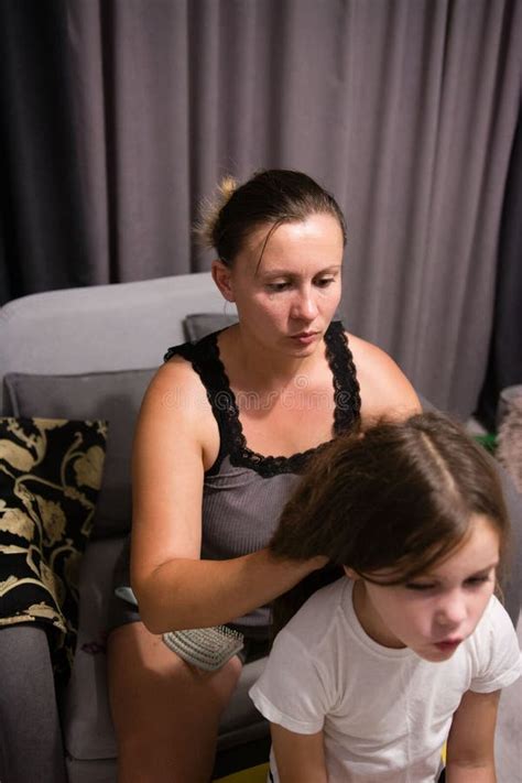 A Mother Gently Brushes Her Daughterand X27s Long Hair While Sitting On A Couch Stock Image
