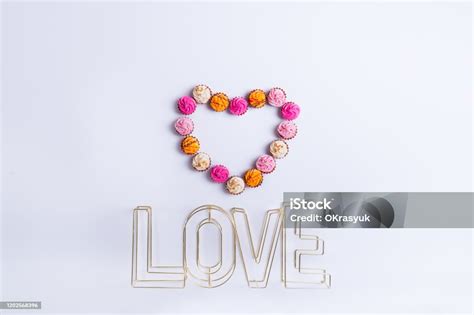 하트 모양으로 배열 된 여러 가지 빛깔의 크림 충전과 모든 종류의 초콜릿 과자의 상단보기 축제 구성고립 흰색 배경에 와이어 단어 사랑 해피 발렌타인 데이 공간을 복사합니다