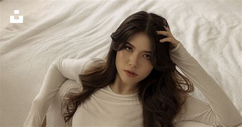 흰색 긴 소매 셔츠와 검은 반바지를 입은 여자가 하얀 침대에 앉아 있다 사진 Unsplash의 무료 포트레이트 이미지