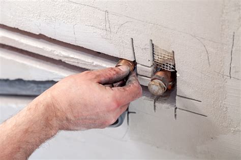 전문 마스터 배관공의 클로즈업 손욕실 콘크리트 벽에 물 구리 파이프를 설치합니다 개념 파괴 설치 아파트 건물 파이프 라인의 변경 누수 리노베이션 강철에 대한 스톡 사진 및