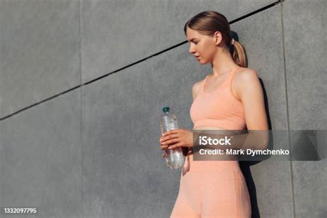 병에서 물을 마시는 젊은 여성의 사진 피트니스 운동 선수 여성은 운동 후 물을 마시고 도시 벽 배경에 대해 야외 운동 건강한 생활방식에 대한 스톡 사진 및 기타 이미지