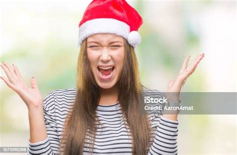 이상의 크리스마스 모자를 입고 젊은 아름 다운 백인 여자 배경 축 제기 및 닫힌 눈 비명 흥분 하는 무기와 성공을 위해 미친