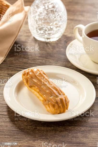 화이트 플레이트에 바닐라 소스를 얹은 홈메이드 에클레어 디저트와 나무 테이블에 차 한 잔 가득 찬에 대한 스톡 사진 및 기타 이미지 가득 찬 갈색 거품 내기 Istock