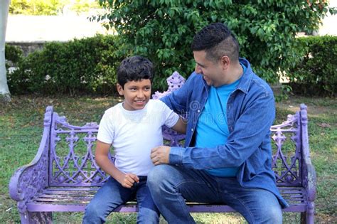 Divorced Dad On A Park Bench With His 10 Year Old Dark Skinned Latino Son Spending Quality Time