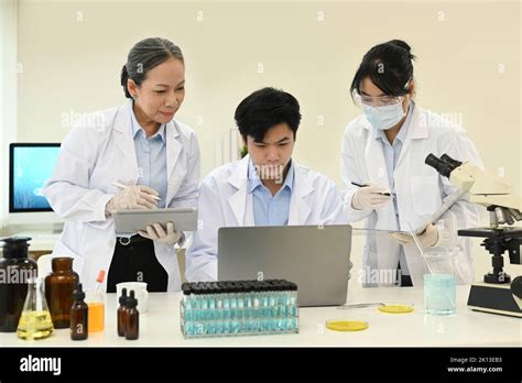 Senior Woman Scientist And Young Researcher Collecting Data And Summarising Information For