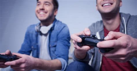 잘 생긴 젊은이들이 집에서 플레이 스테이션에서 경쟁하고 있습니다 그들은 앉아서 웃고 있습니다 게임 컨트롤러를 들고 있는 팔에 집중하세요 사진 Unsplash의 컴퓨터 이미지