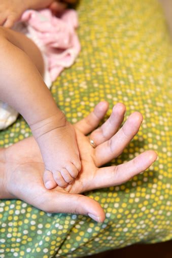 엄마의 손에 갓 태어난 아기의 작은 발 행복한 가족과 가정의 개념 녹색 담요 배경입니다 건강 소아과 아름 다운 클로즈업 이미지 열린 손바닥과 작은 손가락 2명에 대한 스톡