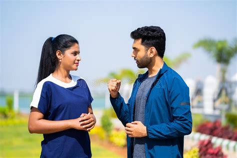 Serious Young Indian People Doing Stretching Exercise By Touching Feet Vy Sitting On Park Serious Young Indian People Doing Stretching Exercise By Touching Feet Vy Sitting On Park