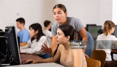 Schülerin Die Computer Benutzt Und Lehrerin Die Ihm Im Klassenzimmer