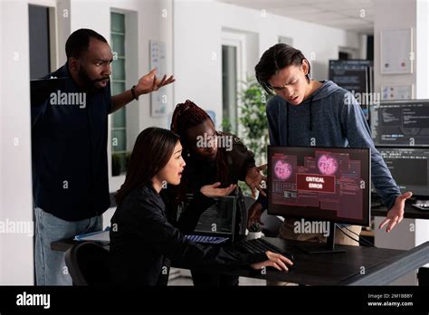 team of it programmers having web server hacked looking at critical error on computer monitor