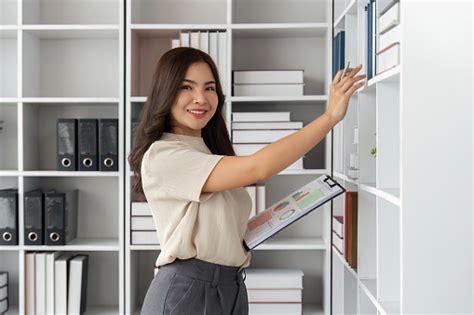매력적인 사업가가 선반에서 서류가 담긴 폴더를 꺼낸다 사무실에서 서류를 가지고 일하는 여자 경영자에 대한 스톡 사진 및 기타 이미지 Istock