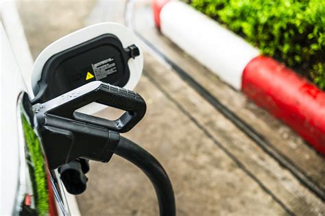 흰색 자동차에 연결된 전기 자동차 충전 핸들을 클로즈업하여 지속 가능하고 깨끗한 에너지 솔루션을 홍보합니다 친환경 교통수단과 친환경 모빌리티의 개념 0명에 대한 스톡 사진