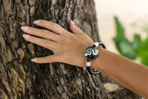 Рука молодой женщины с Handmade браслетом кожи на предпосылке дерева Стоковое Фото изображение