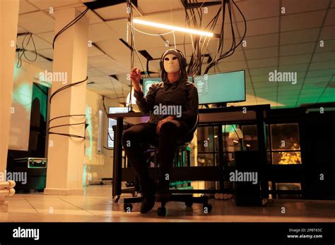 Hacker With Mask Looking At Holographic Image In Augmented Reality Working With Hologram To