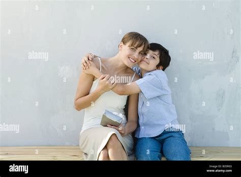 Mother And Son Embracing Woman Holding Gift Both Smiling At Camera Stock Photo Alamy